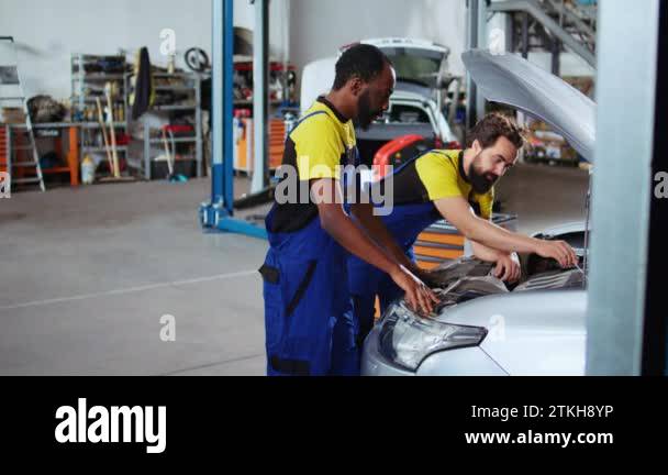 Certified engineers in auto repair shop working together on fixing car ...