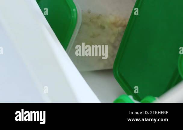 The woman carefully puts the ready food into a container for storage ...