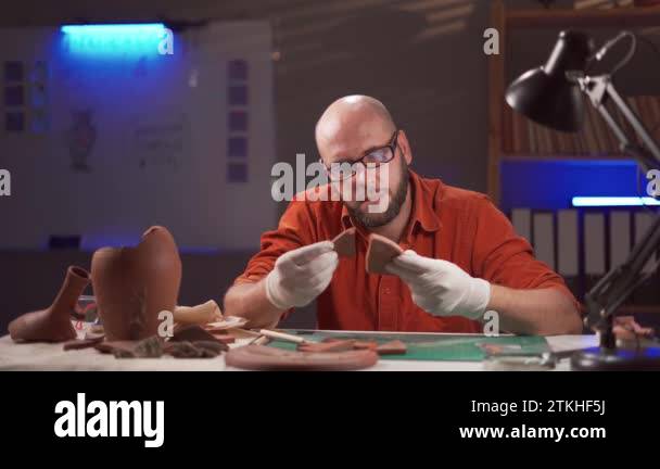 Archaeologist man working in the office late night. Studying artifacts ...