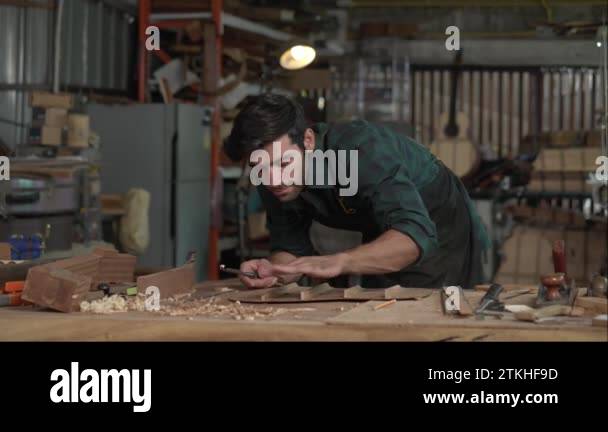 A skilled luthier is hard at work sanding the body of an acoustic ...