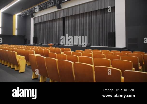 Chair rows and stage with black curtain in empty hall of theatre ...