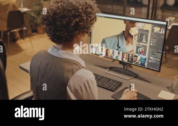 Back view of Caucasian woman sitting at desk in office retouching photo ...