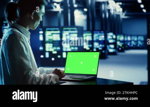 Employee using chroma key laptop to fix data center hardware clusters ...