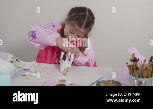 Little girl painting paper mache figurine at homeschooling art class ...