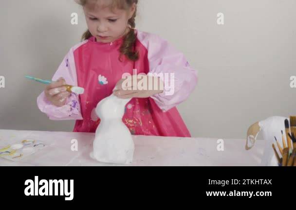 Little girl painting paper mache figurine at homeschooling art class ...