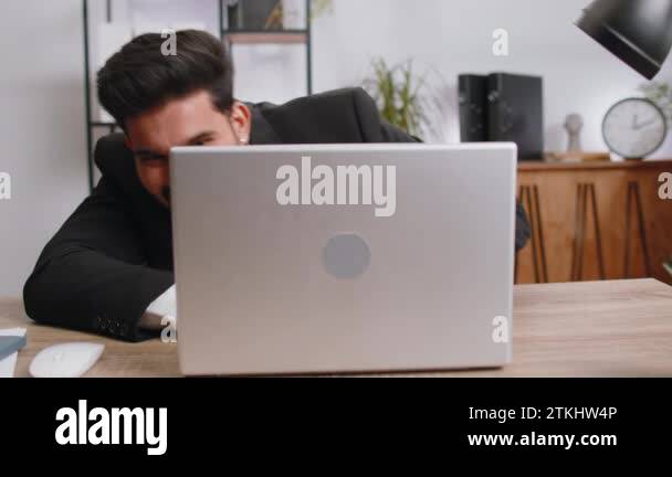Indian businessman hiding behind laptop computer, making funny face ...