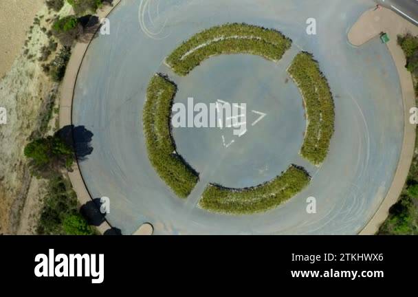 Zoom in empty asphalt roundabout intersection with green hedge and ...
