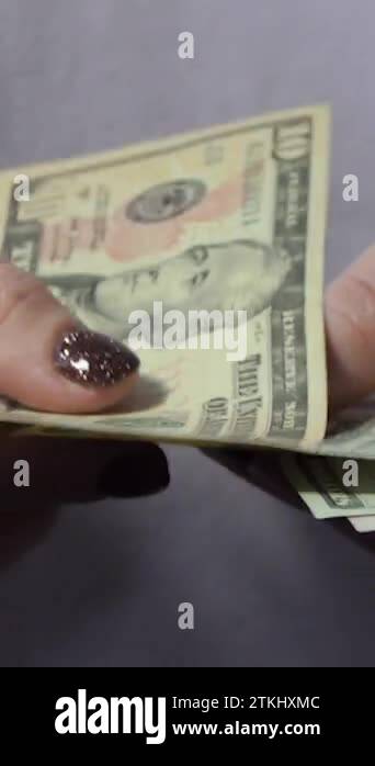 Vertical Screen: close-up of female hands of hands counting US dollar bills. girl counts cash ...