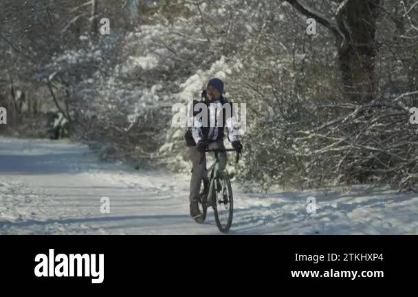 Male cyclist cycling in park on snow during winter on sunny weather in ...