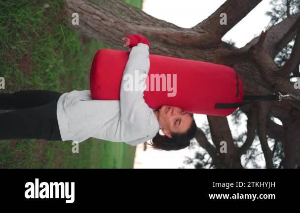 Fitness woman training boxing punching bag outside in outdoor gym ...