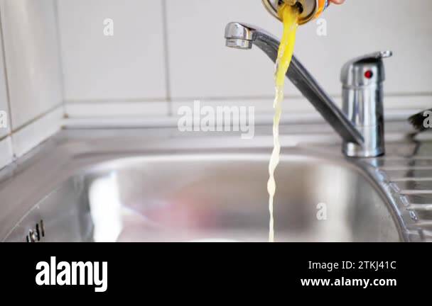 A hand holding a soda can pours the drink into the sink, unhealthy ...