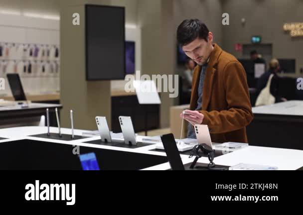 Young caucasian recognizable man in a brown coat examines a smartag for ...
