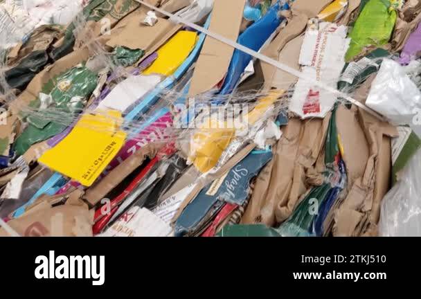 A large stack of waste paper from pressed cardboard boxes is sorted and ...