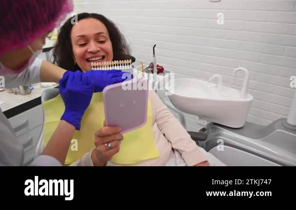 Dentist doctor placing a tooth color chart, over a beautiful smiling ...