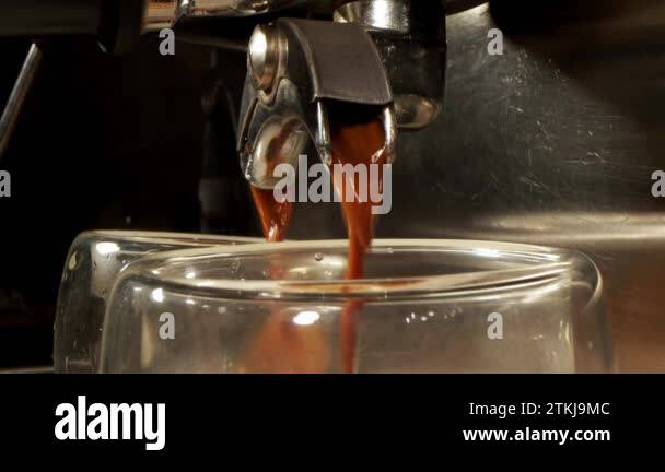Pouring a coffee jet from a professional machine into a cup. A man ...