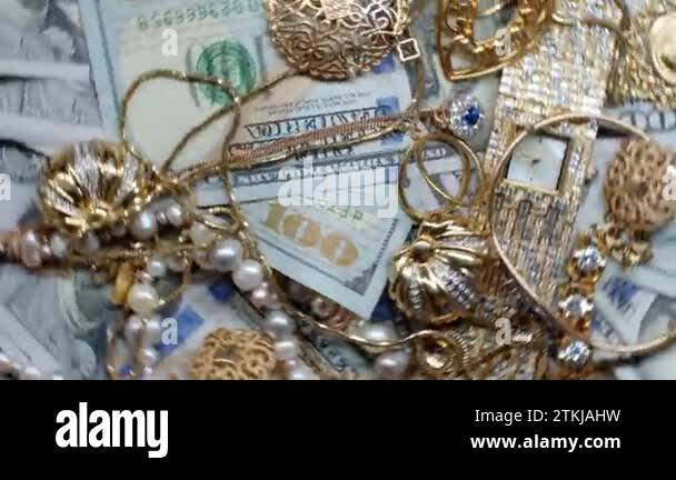 4k rotating footage of many one hundred dollar bills and gold jewelry ...
