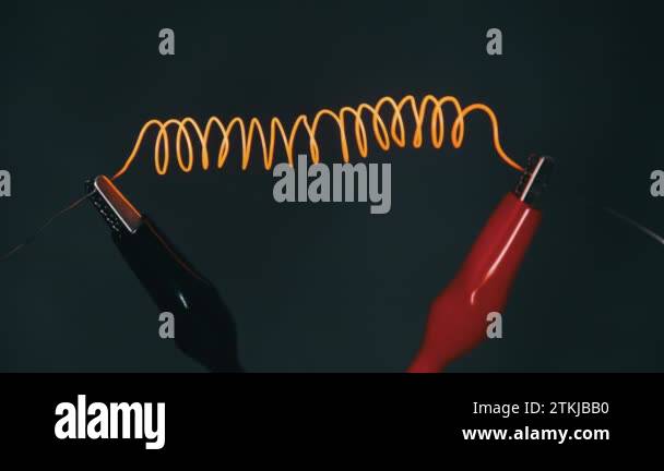 Nichrome filament connected to power wires is heated to red under the ...