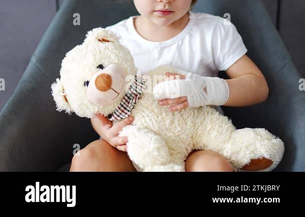Little girl with broken finger holds teddy bear with a bandaged paw at ...