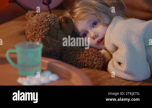 Close up of sick child resting on the sofa, watching TV, struggling of ...