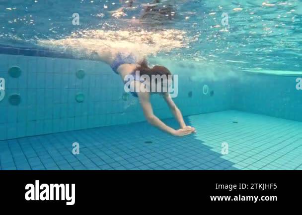 Beautiful girl teenager swimming in pool under water in bikini, side ...