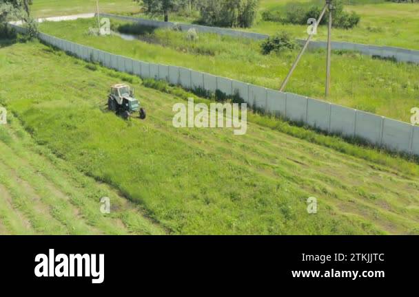 Summer Haymaking with a tractor mower. Tractor mows green grass to dry ...
