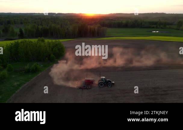 Harrow system plowing ground on cultivated farm field, pillar of dust ...