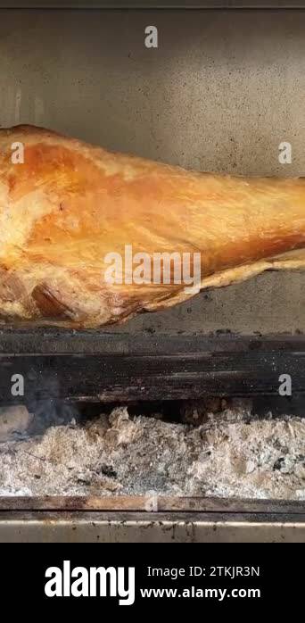 Roasting whole lamb on a spit metal rotating stick over fire, golden ...