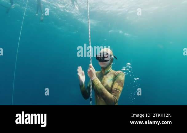 Freediving on the rope in a sea. Confident female freediver slowly ...