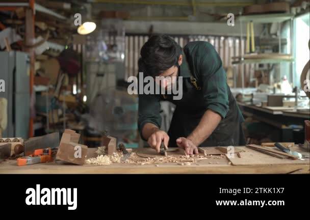 A skilled luthier is hard at work sanding the body of an acoustic ...