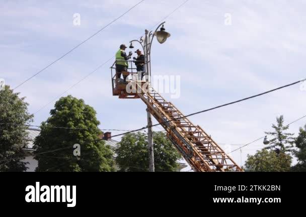 repair street lamp, crane lifted, light bulb. Worker is fixing street ...
