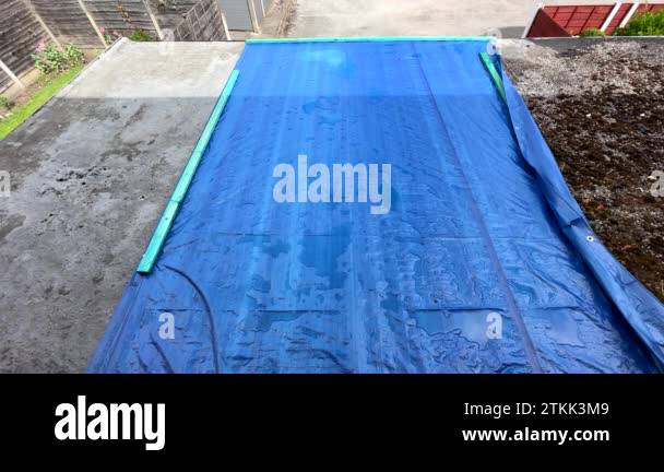 Temporary blue plastic sheet covering leaking part of flat roof of one ...
