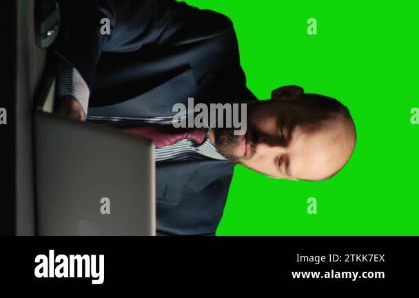 Vertical video: Executive manager using laptop over green screen ...