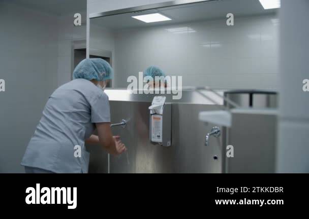 Surgeon in uniform washes hands with soap before surgery. Female medic ...