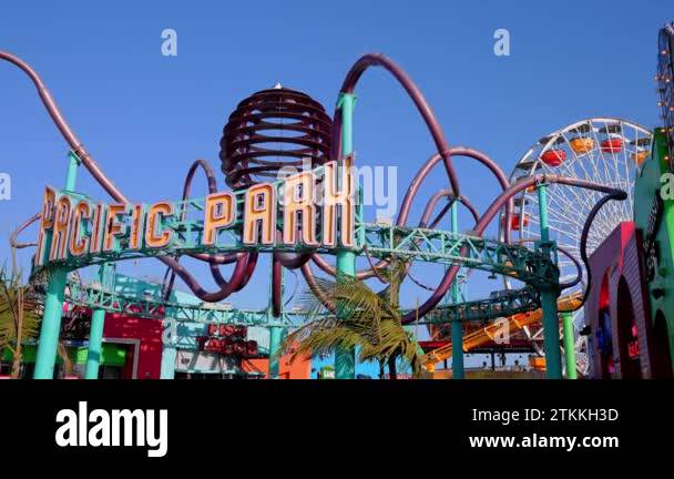 Ferris wheel and roller coaster rides and people exploring shops at the ...