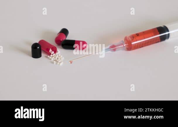 Demonstration of drugs in black and red capsules and in a syringe. One ...