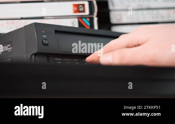 Eject VHS tape cassette from VCR player. Male hand pulls out VHS from a ...