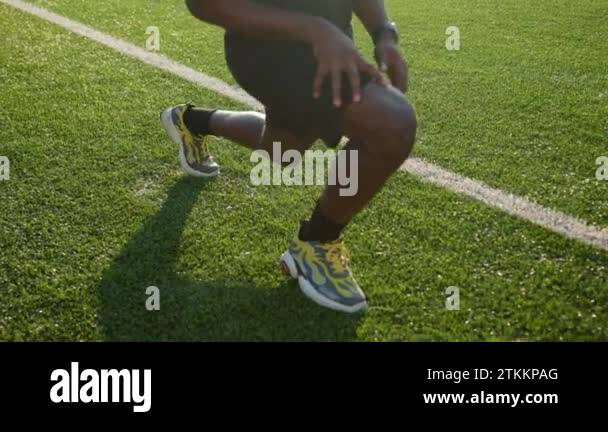Strong sportsman African American athletic male footballer doing lunges ...