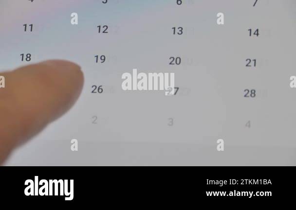 Close-up of a smartphone, finger scrolls through calendar looking for ...
