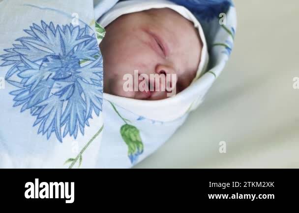 Swaddled newborn baby open eyes, squint from daylight, yawning ...