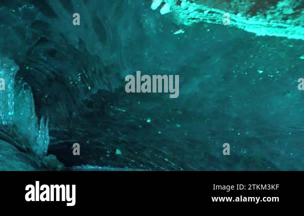Turquoise pure color of ice inside the ice cave. Stones and icicles are ...