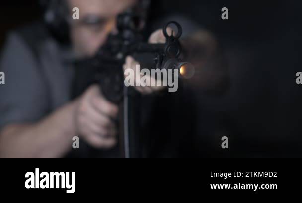 Close-up of man aiming and firing an assault rifle in slow-motion ...