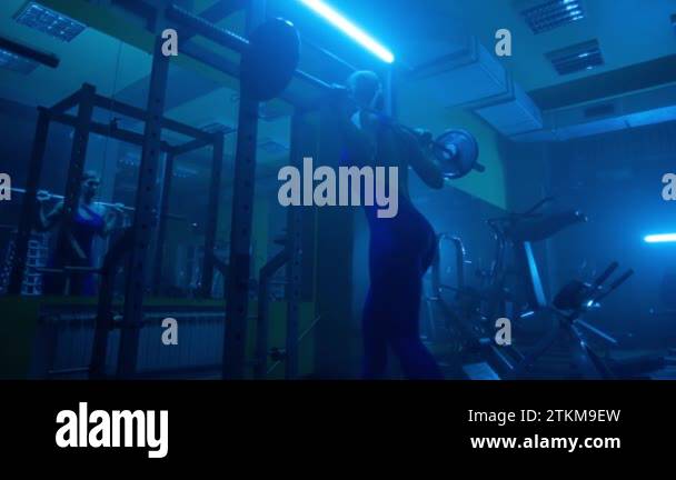 Side view of dark silhouette of woman with slender body is squatting ...