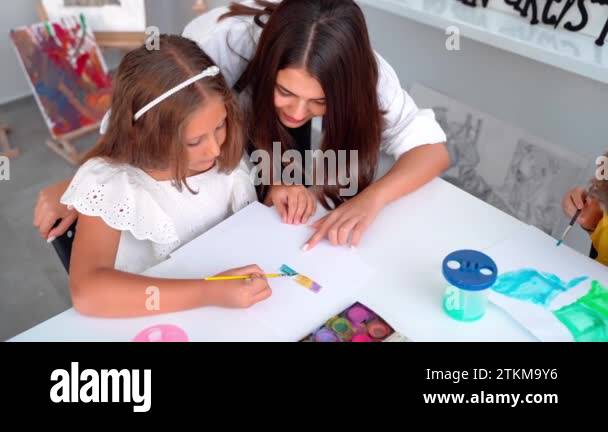 Teacher At Art School Helping Children in Art Class with painting ...