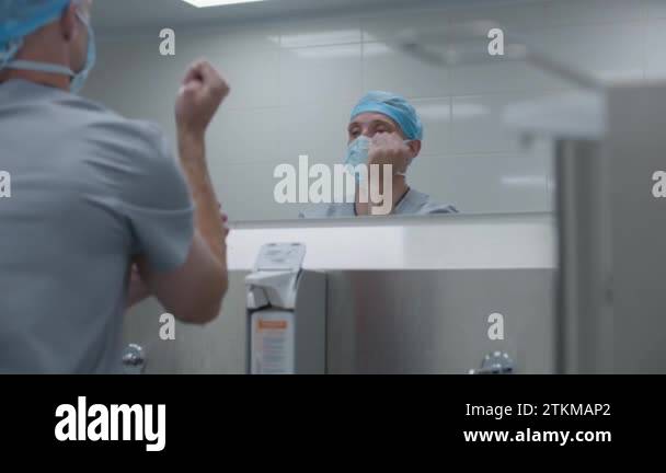 Surgeon in uniform cleans hands with soap before surgery. Male medic ...