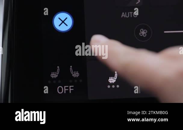 Hand pressing the steering wheel heating control panel in the car ...