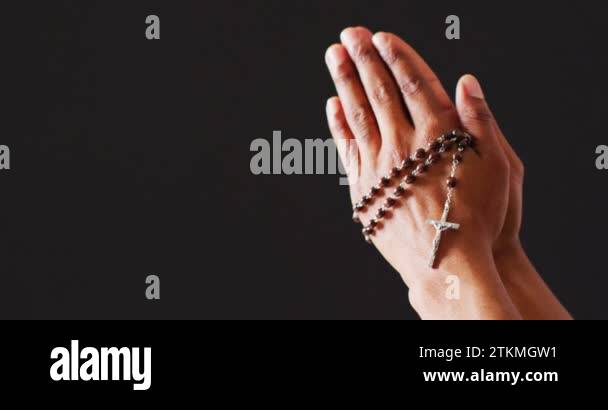 Praying hands with rosary on black background with copy space. Easter, faith, religion ...