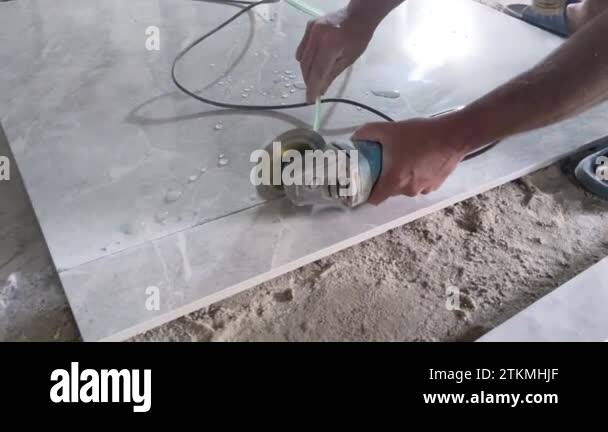 Man cutting a big floor tile with an angle grinder tool. Raw footage of ...