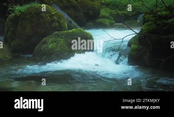 Steam rises from the surface of a fast-flowing river in a mountain ...