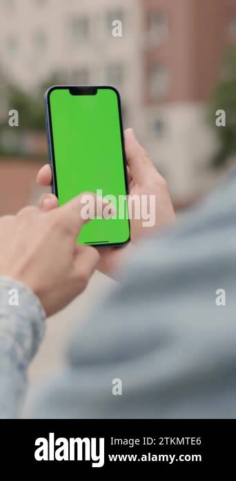 Close Up Of Phone With Vertical Green Screen In Men's Hands On City ...