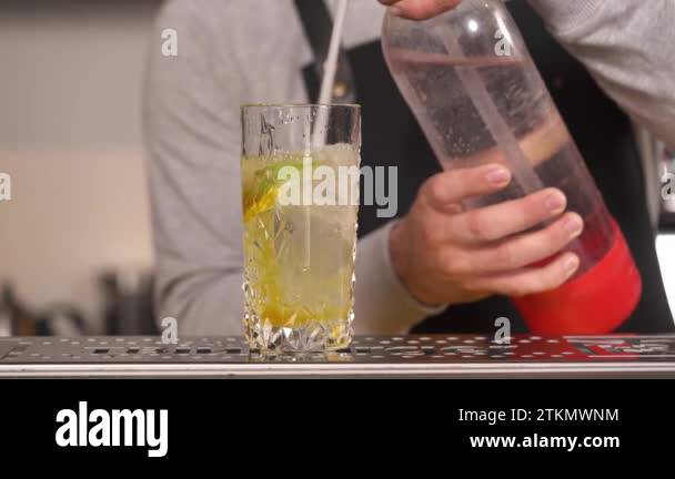 A close-up of a bartender pouring sparkling water from the soda siphon to the glass with fresh ...